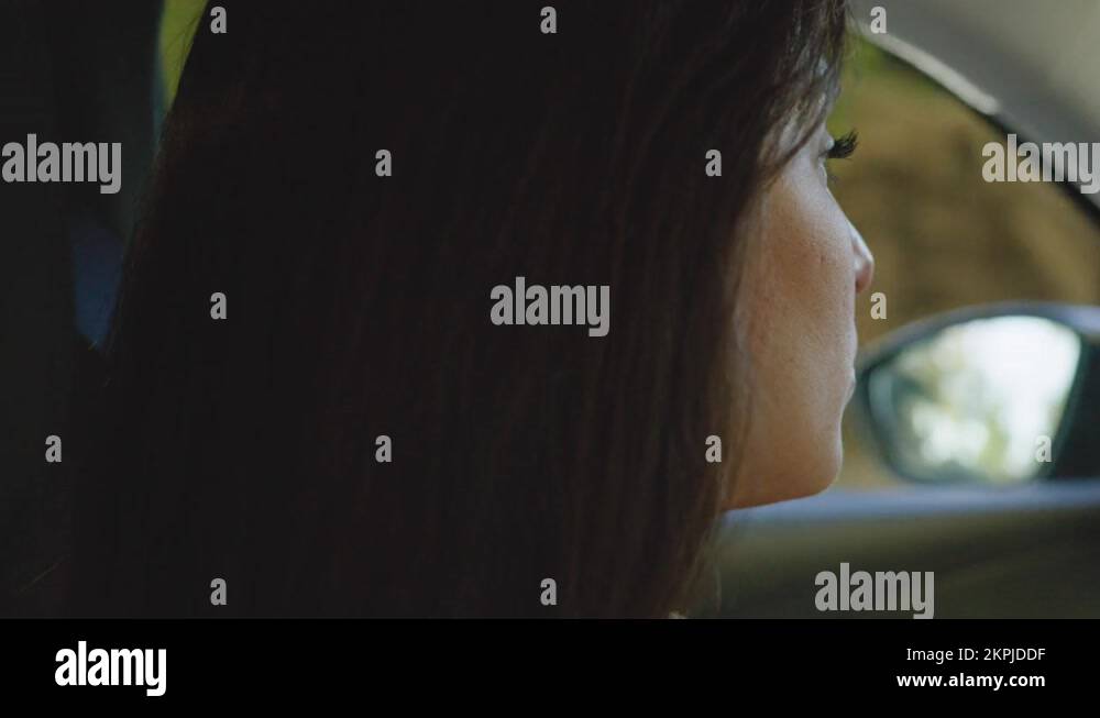 Close up, side profile of a young woman driving a car with a serious ...