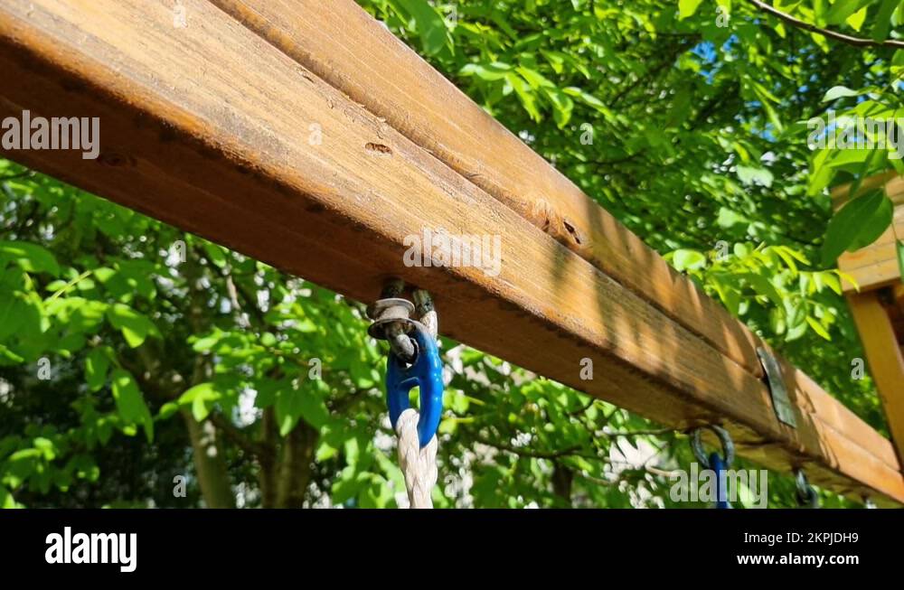 Rope and broken metal ring mount on wooden timber of a garden swing ...