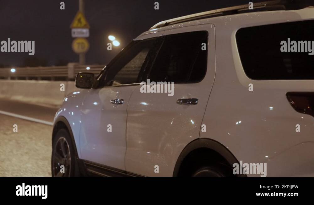 Back view of white tinted SUV car driving on wet asphalt road in the ...