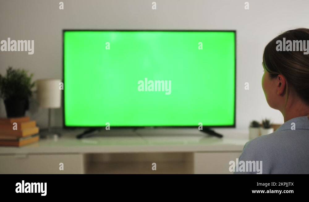 Woman watching TV with green screen switching channels, using remote ...
