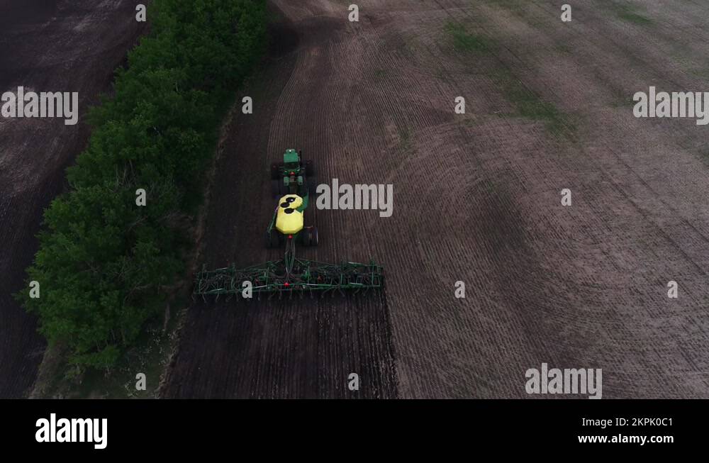 A high-angle shot following a John Deere tractor seeding a field Stock ...