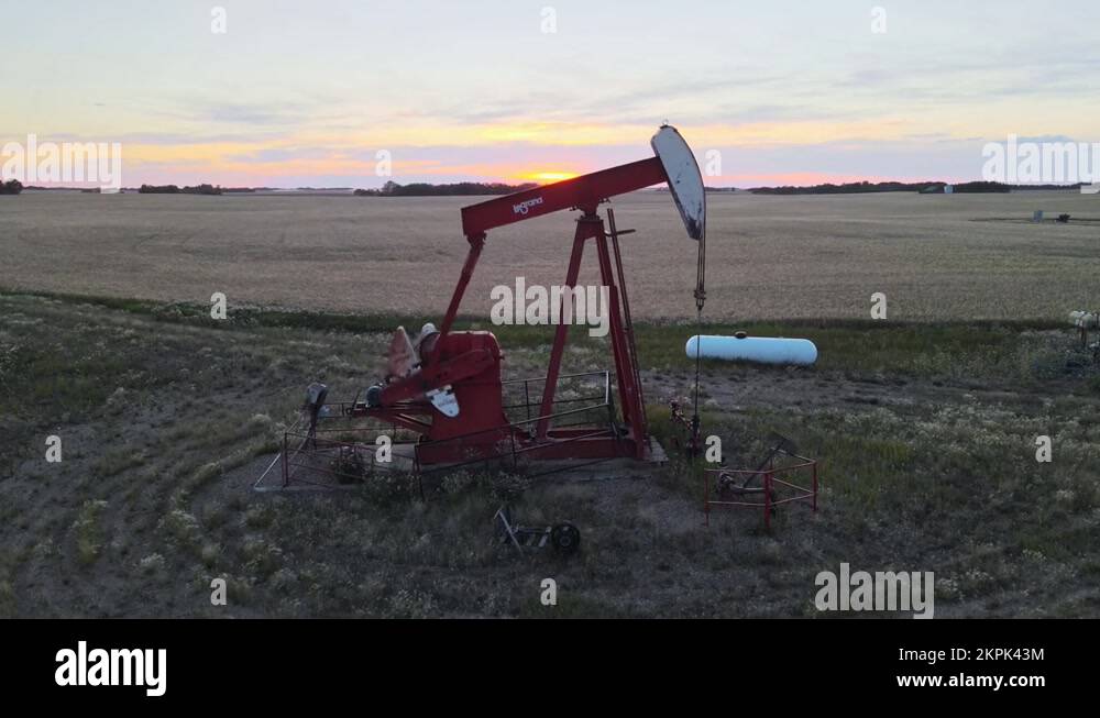 Pumpjack extracting crude oil in the Canadian prairies at sunset. Wide ...