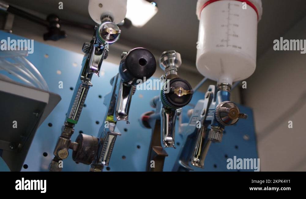 four spray guns in cabinet. High-precision airbrushes hang next to ...