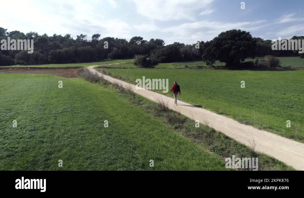 Young man walking alone on the country gravel road somewhere in an ...