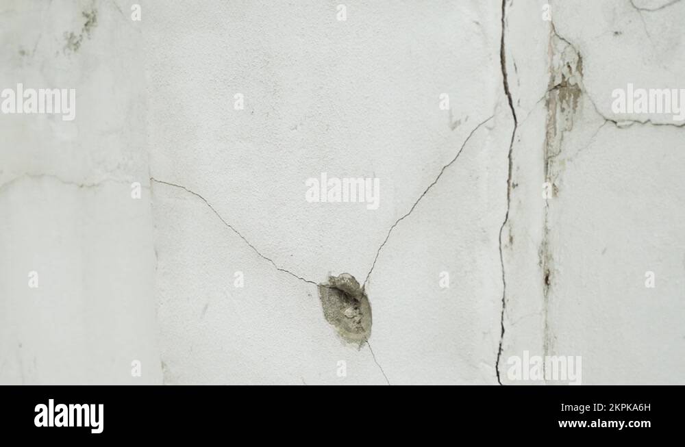 Poor quality aged building with cracks in the white walls of the facade ...