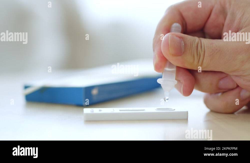 CLoseup hand using rapid antigen test kit (ATK) for self test at home ...