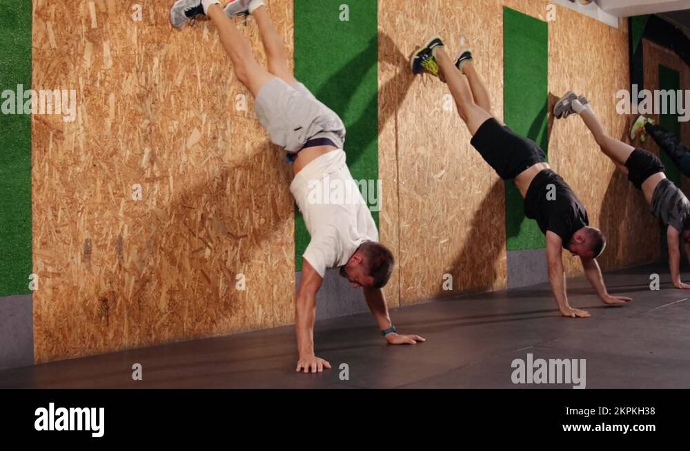 Athlete walks on hands while standing upside down near wall. Full body ...
