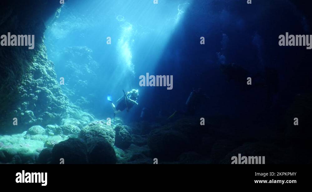 sun light rays beams underwater cave scuba divers to see ocean scenery ...