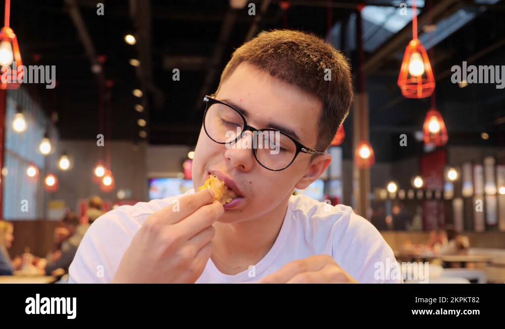Funny attractive guy in a white shirt and glasses is eating fried ...