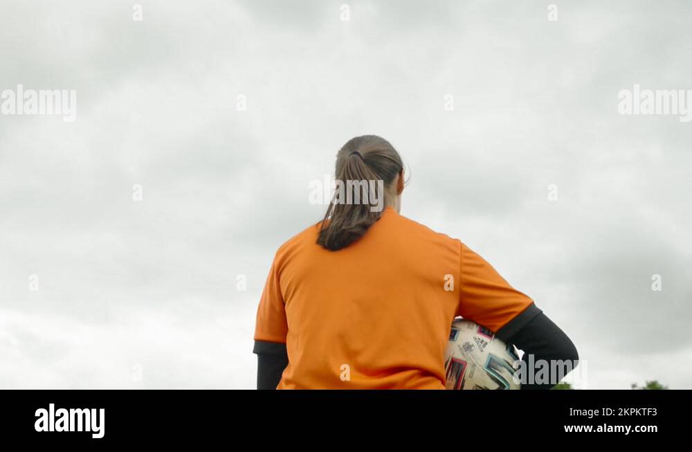 Female referee walking on the football pitch holding the soccer ball ...