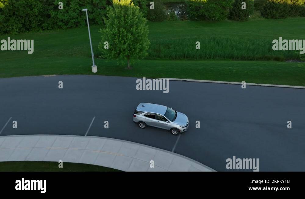 Aerial tracking shot of SUV driving in school parking lot. Drone using ...