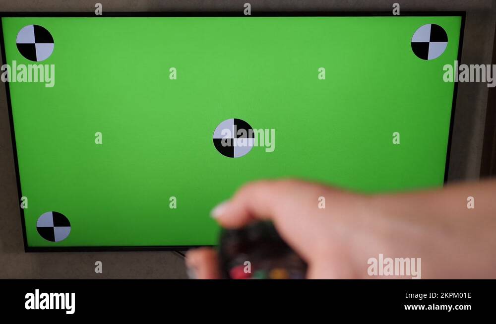 Hand holding TV remote controller over green screen a modern television ...