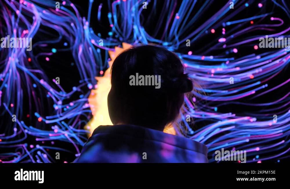 Back view: woman looking around against large wall display at immersive ...