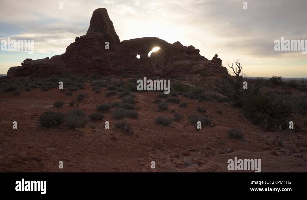 Tilt up to reveal sun peeking through Turret Arch at Arches National ...