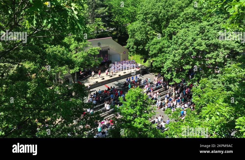 Aerial framing among trees of outdoor concert. Crowd of people gather ...