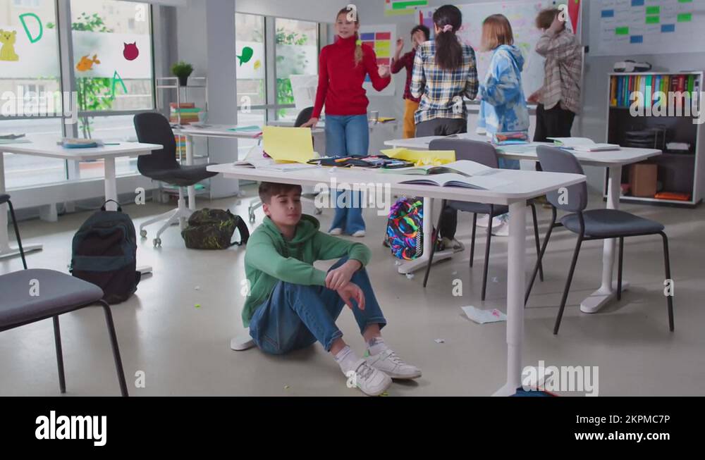 Teenage boy sit and cry under desk in classroom. Bullying at school ...