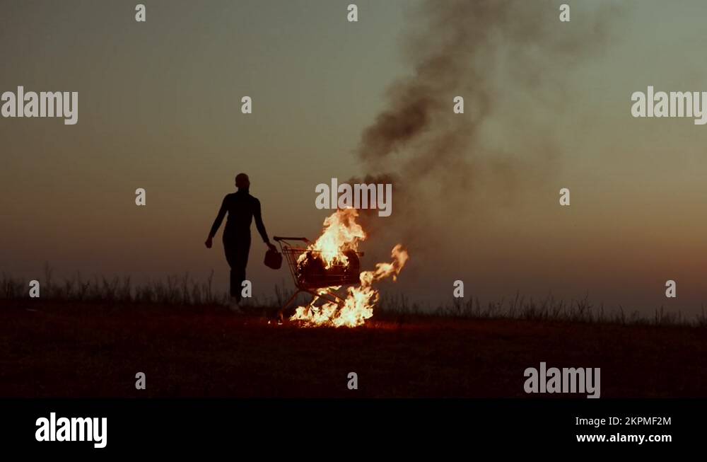 A man pours gasoline from a canister on a burning cart from a ...