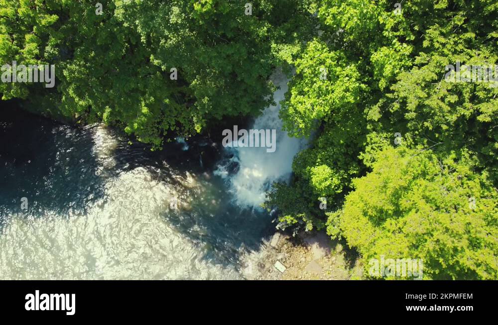 birds-eye view of green forest and small cute waterfall in its depth ...