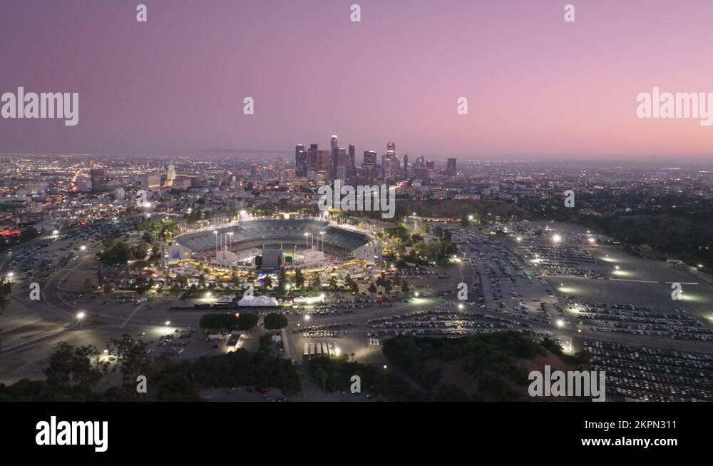 Aerial illuminated universal stadium full of fans, pink sunset sky ...