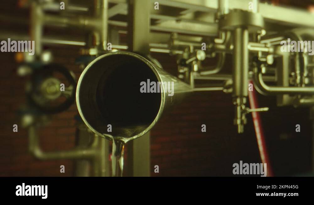 Vodka pouring from tube inside professional alcohol production factory ...