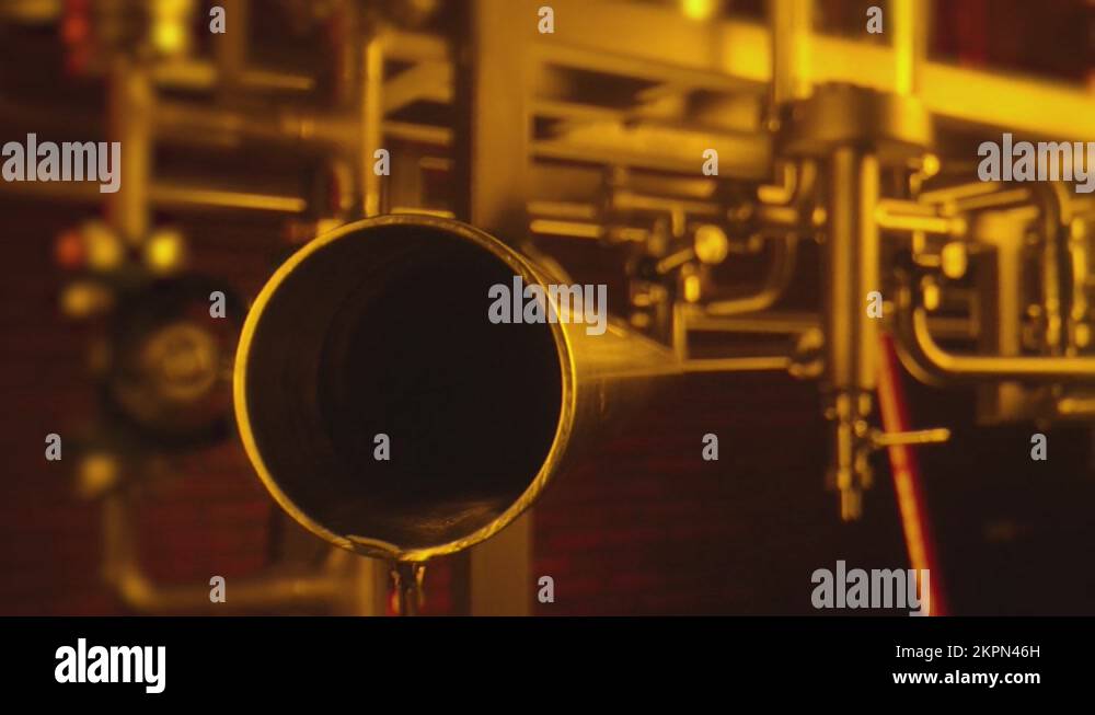 Vodka pouring from tube inside professional alcohol production factory ...