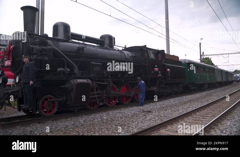 Railroad worker checking wheels of steam train before leaving station ...