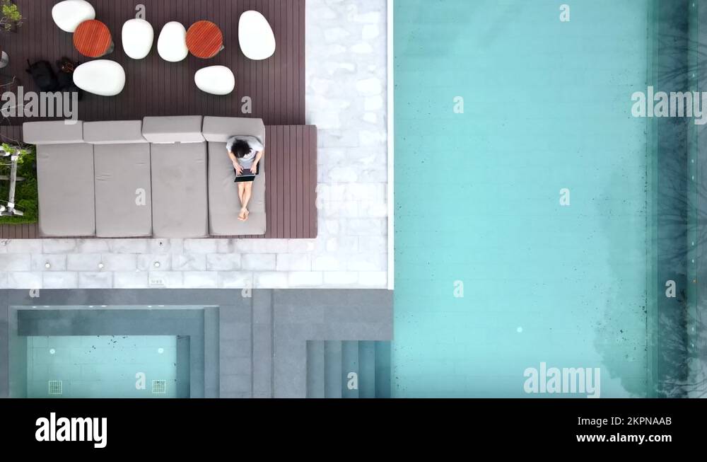 A Remote Worker Leisurely Sitting In A Pool Lounge While Working On His ...