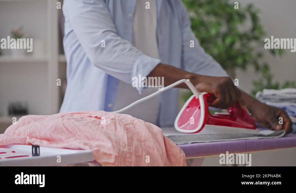 African American male ironing clothes on board, daily routine, house ...