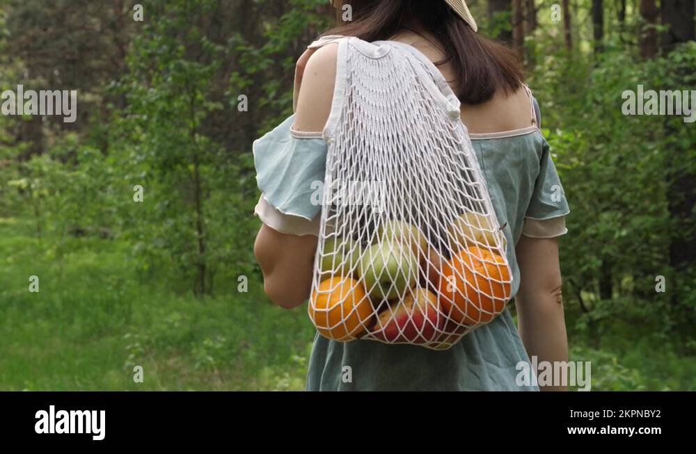 Woman walks with a braided string bag of fresh fruit. Life without ...
