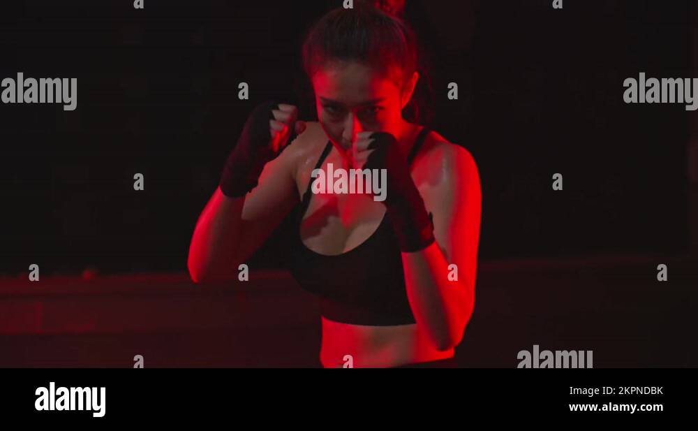 Female boxer practising shadow boxing in dark studio with Silhouette ...