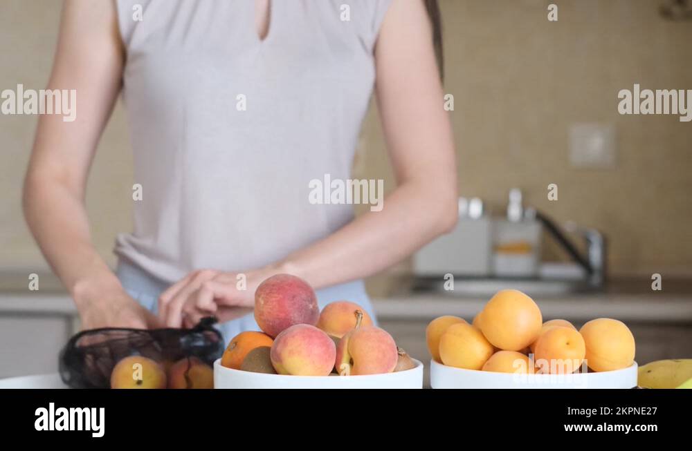 Woman puts ripe fruit in a plate in the kitchen. Vegetarianism, healthy ...
