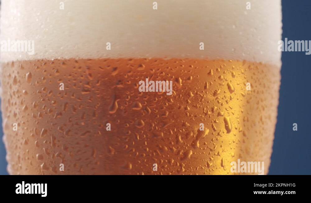 Glass of beer turns slowly around its axis. and the drop flows on the ...
