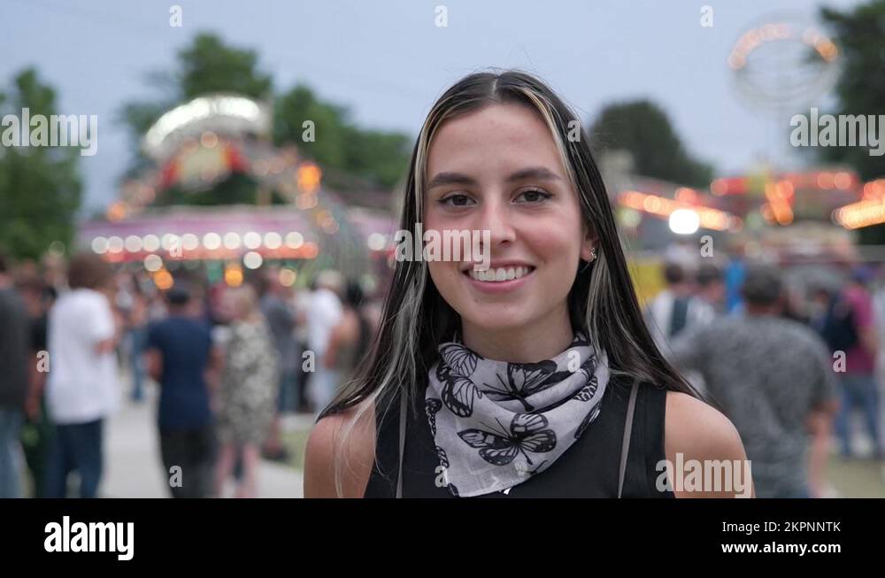 Push in to young woman standing and smiling at a carnival Stock Video ...