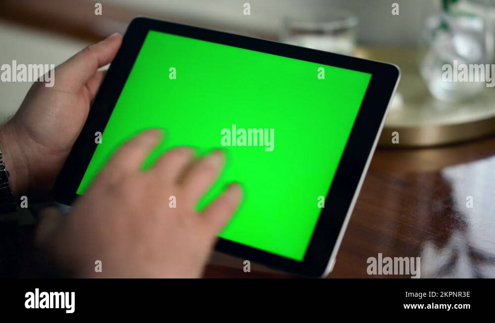 Adult hand swiping green tablet screen closeup. Man holding chroma key ...