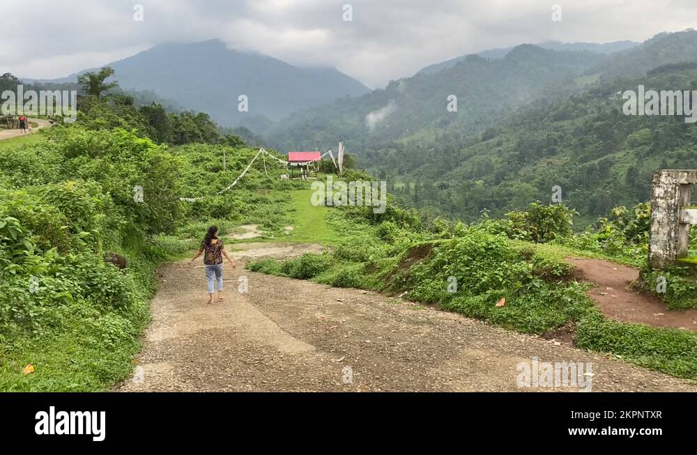 Rear view of Happy young Indian girl walking through mountain roads ...