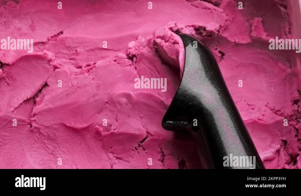 Strawberry ice cream scooping out of container by spoon. Pink ice cream ...