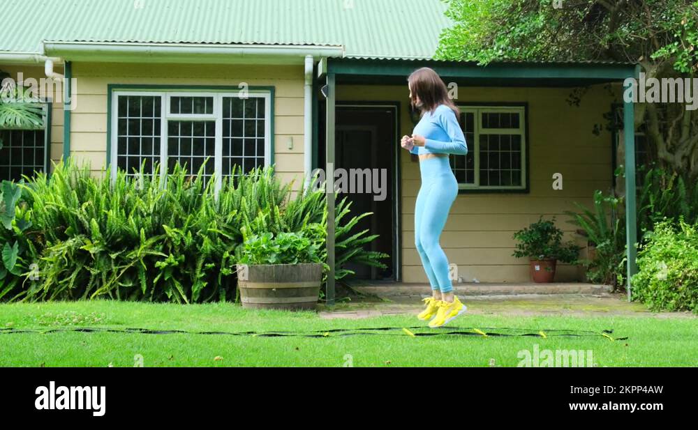 Young Woman Exercise using Agility Ladder. Pretty woman is stepping up ...