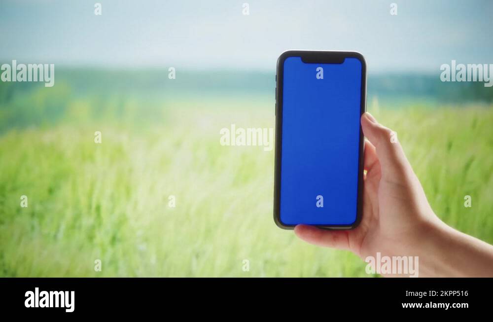 Smartphone with chroma key close-up. Holding mobile phone with blue ...