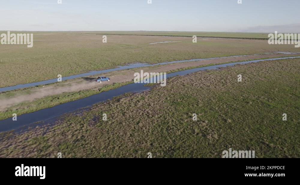 Pick up driving very fast down a dirt road in a field in argentina, at ...