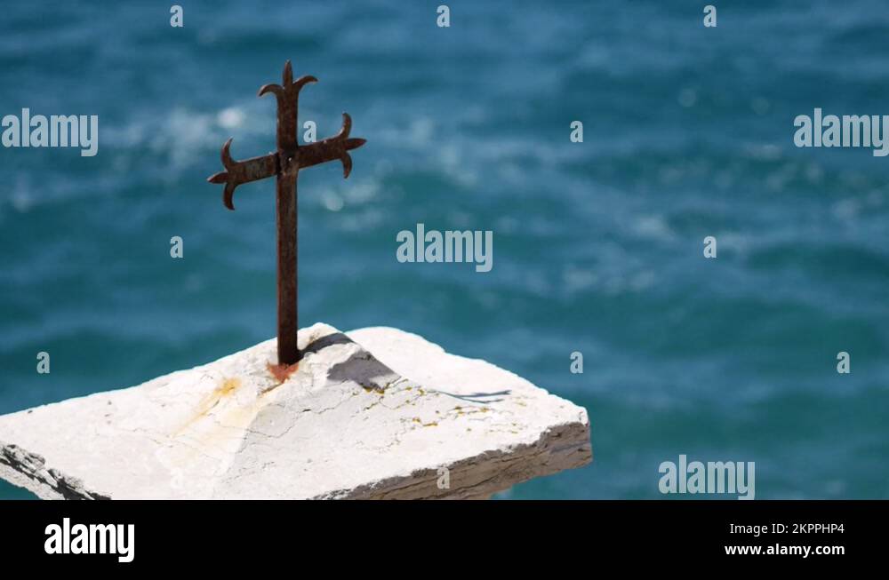 Ancient iron cross on a pedestal on the seashore. Stromy sea background ...