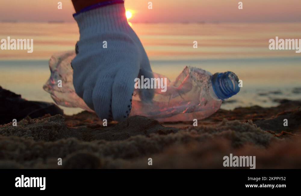 Cleaning plastic garbage on the beach, man collects mud and throws it ...