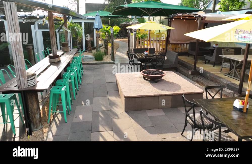 Fire pit and tables at outdoor bar. Aerial flight through tiki bar ...