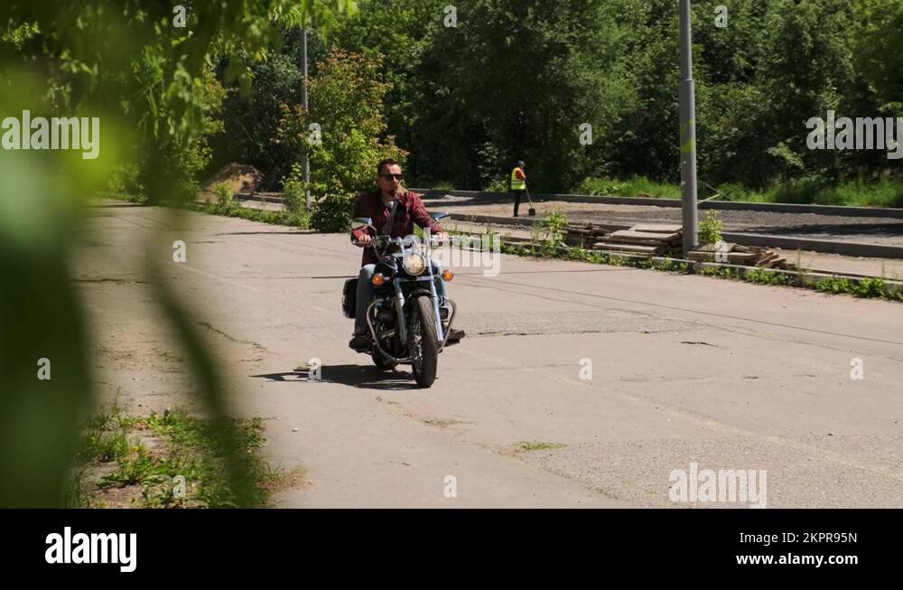 man in red shirt without helmet, wearing black glasses, rides ...