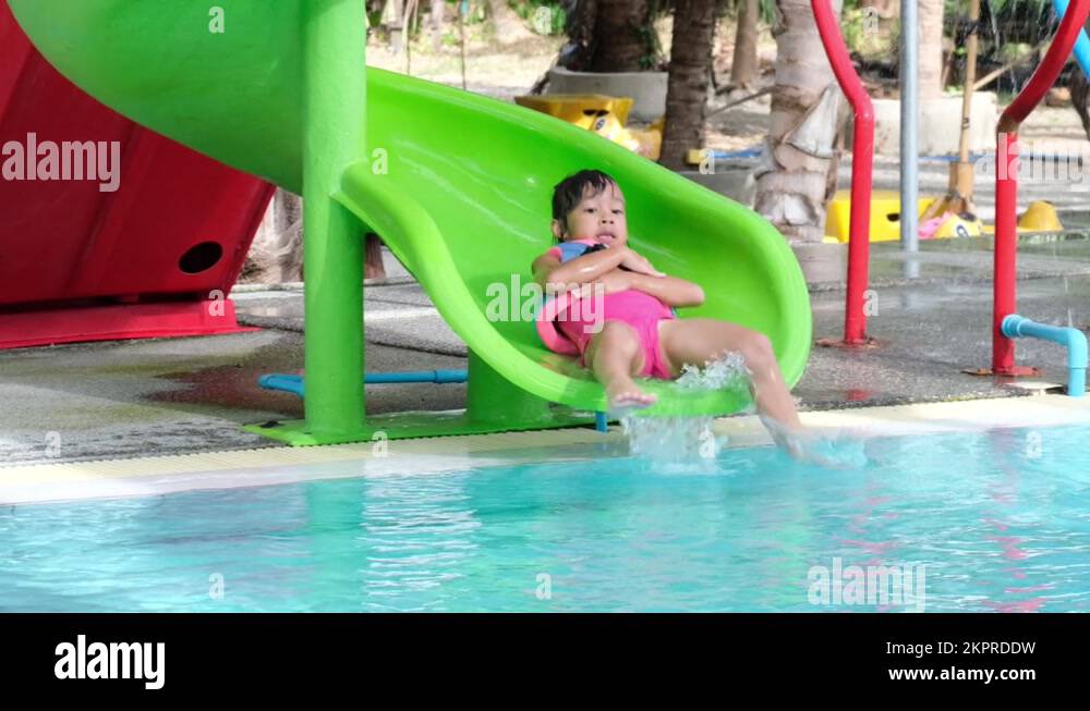 Child on water slide at aquapark. Little girl having fun at swimming ...