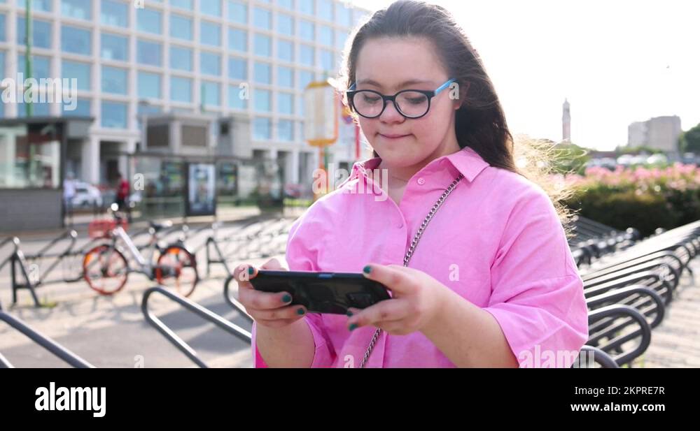 Teenage Girl With Down Syndrome Playing Video Game On Smartphone Stock