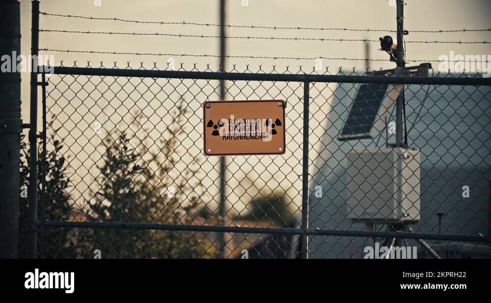 Radiation Danger Sign on Barbed Wire Fence with Butterfly in Slow ...