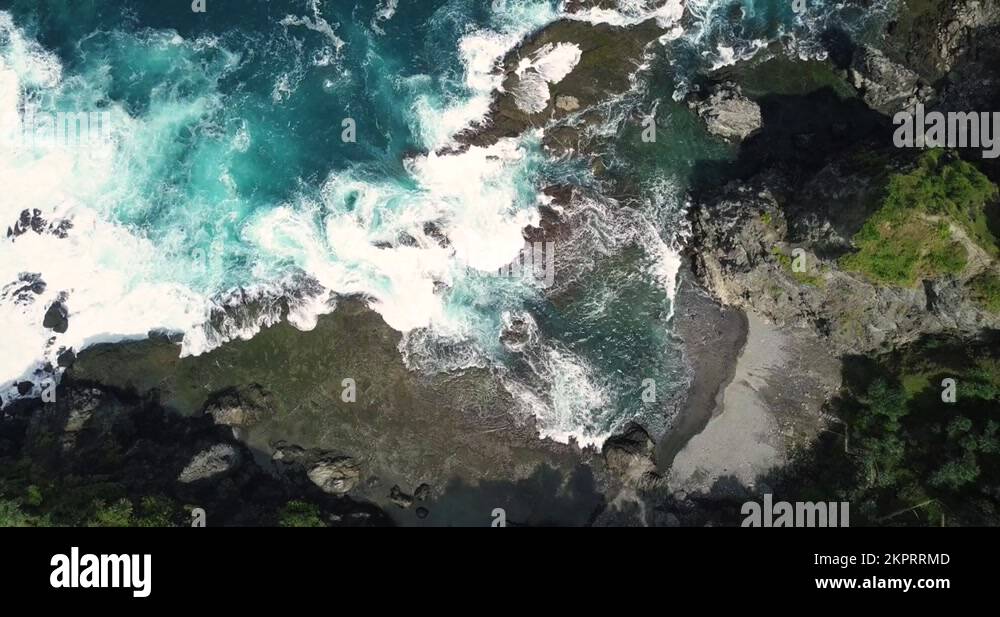 Sliding overhead shot of waves of Indian Ocean hitting boulder and ...