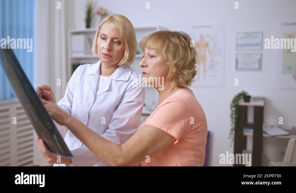 Orthopedist showing female patient x-ray scan, upset with bad recovery ...