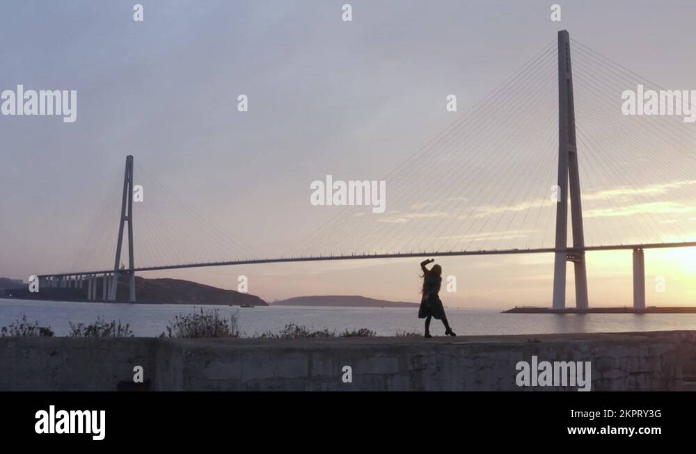 Long haired woman walking and dancing against the rising sun and the ...