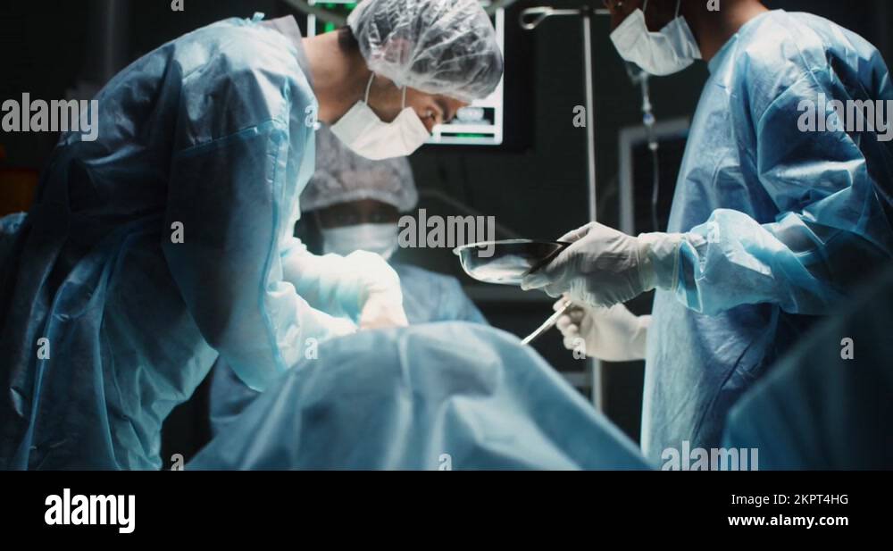 A team of surgeons perform an operation in a bright operating room ...